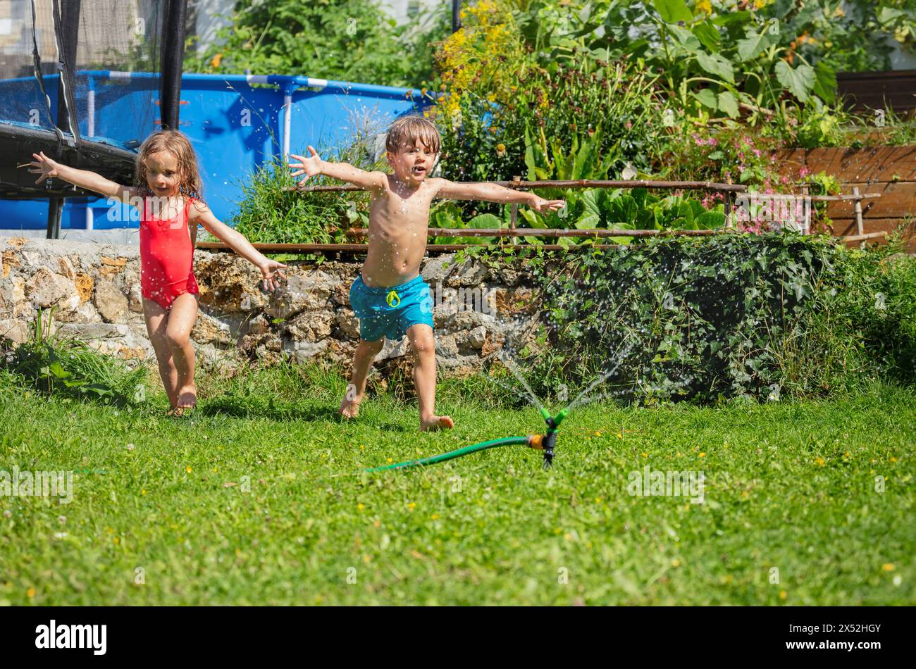 Girl running through sprinkler hi-res stock photography and images - Alamy