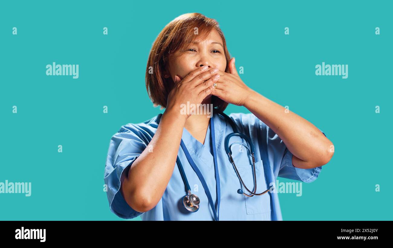 Certified nurse covering mouth with hands, holding back from saying ...