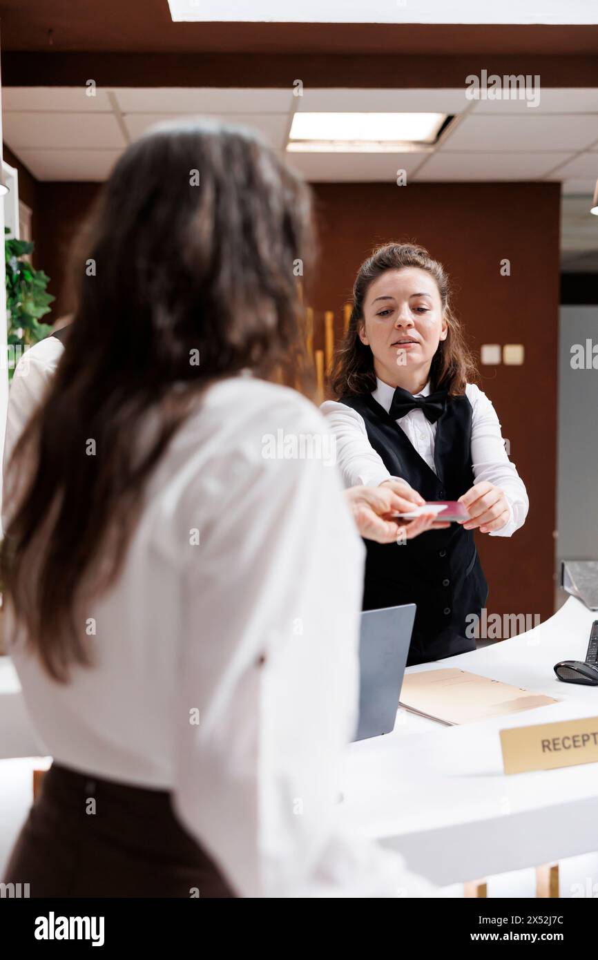 At hotel lobby counter, elderly female traveler checks in with passport ...