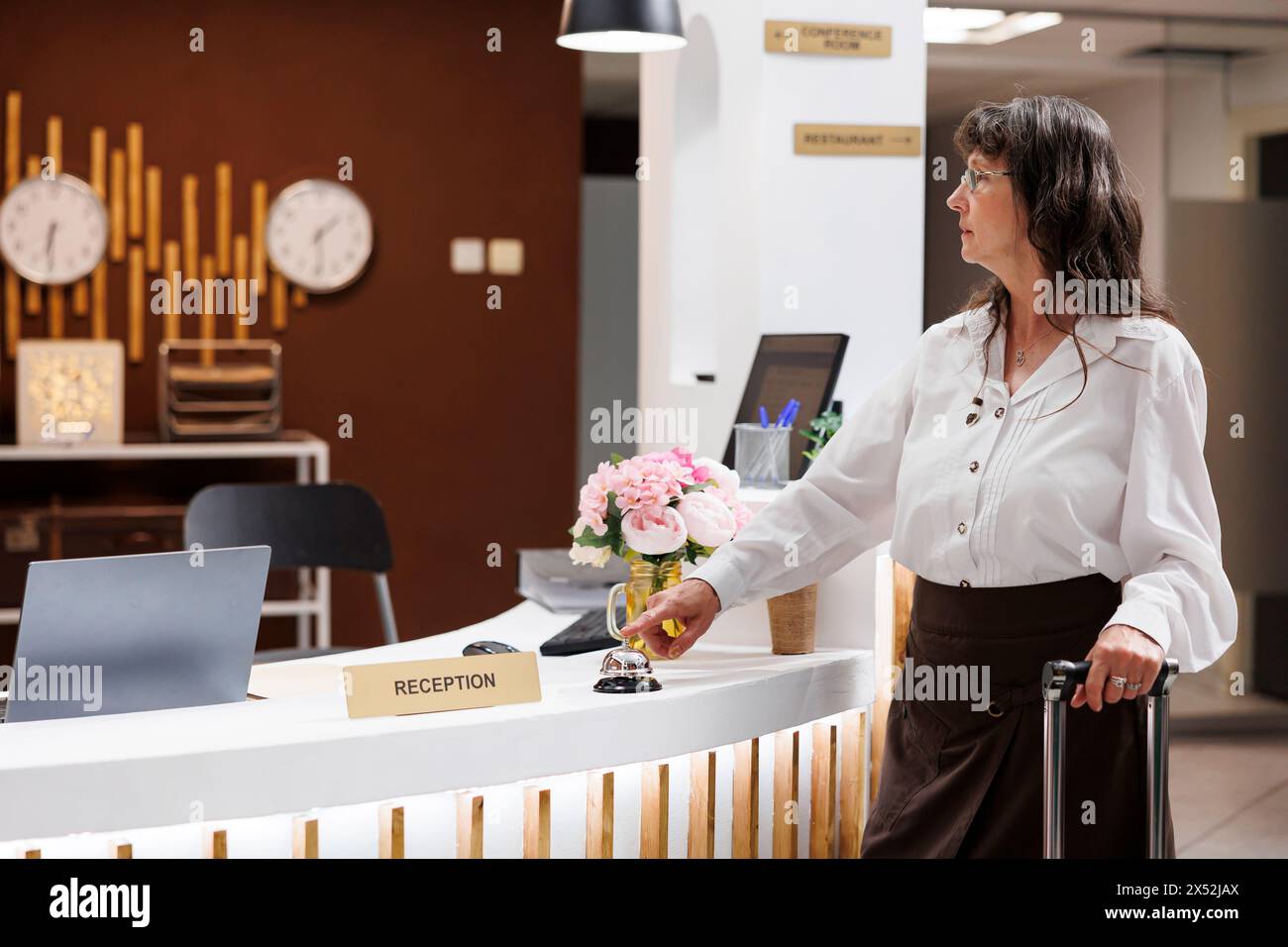 Elderly retired woman approaches the front desk and rings the hotel ...