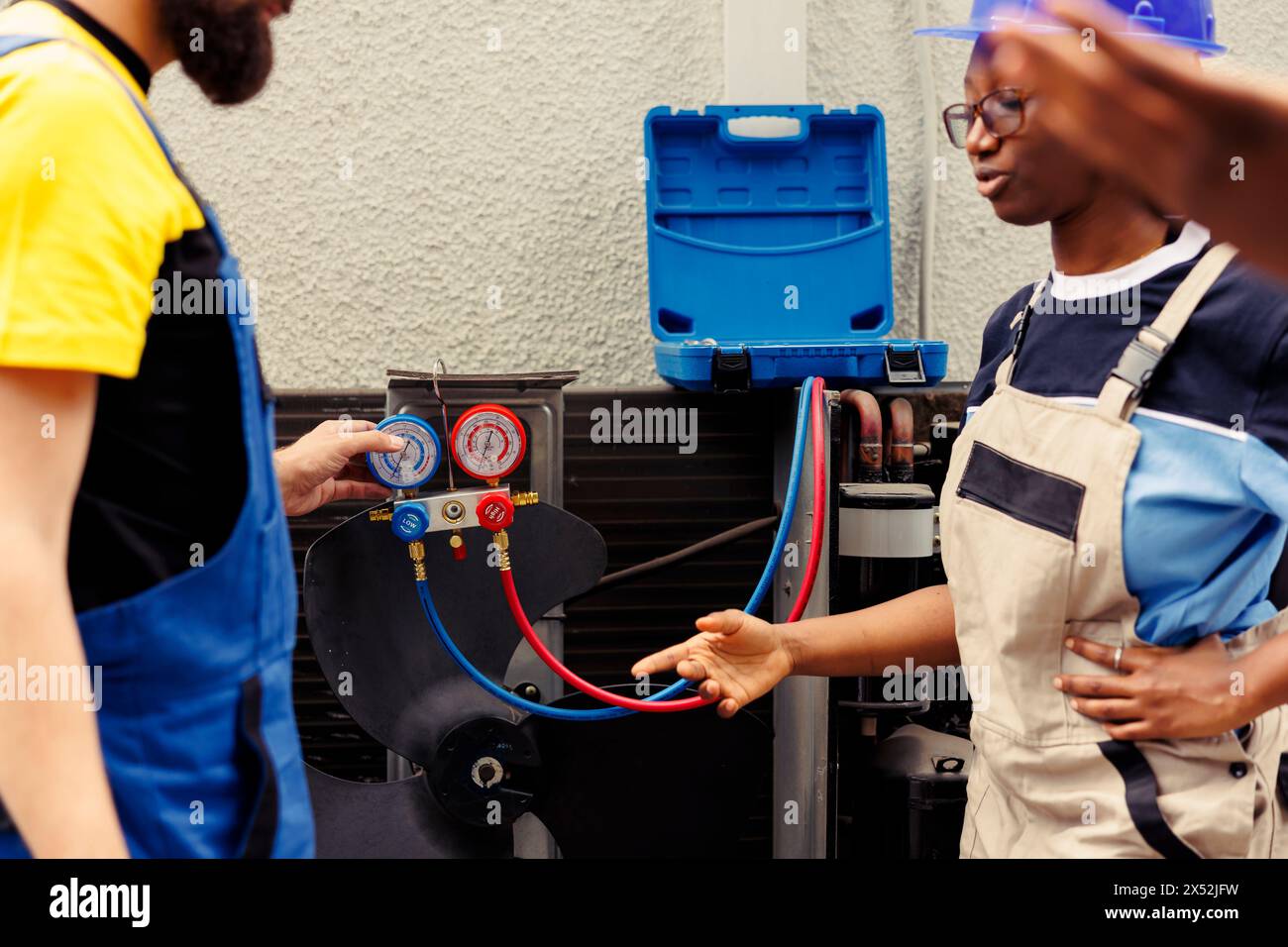 Licensed technicians team working with manifold gauges to check air ...