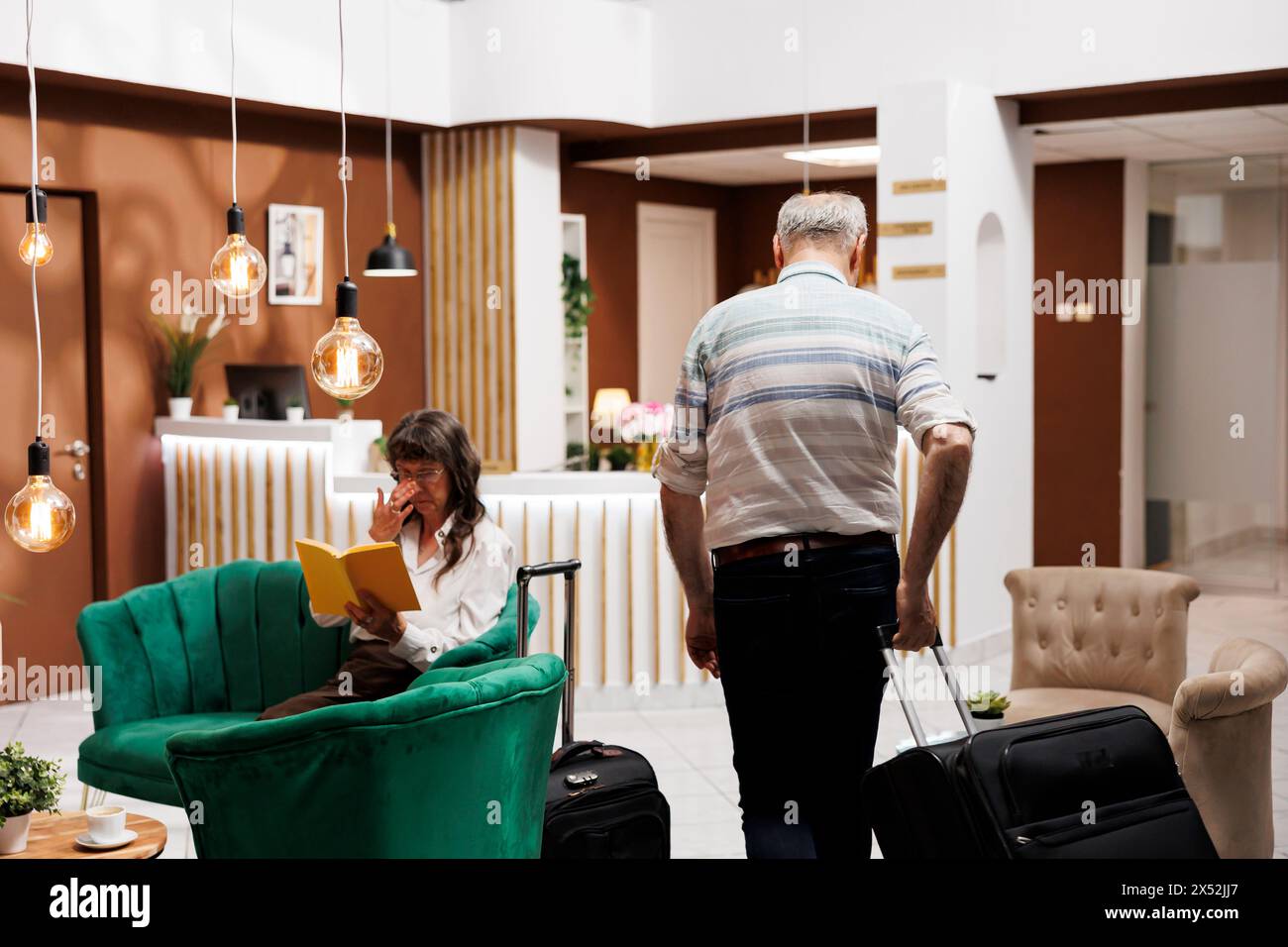 Arriving in contemporary hotel lobby is an elderly caucasian man who ...
