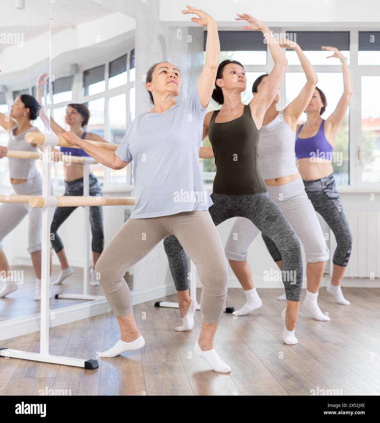 Senior woman performing demi plie at barre at fitness session Stock ...