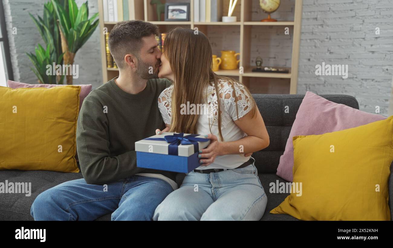 A couple kissing and sharing a gift in a cozy living room, depicting ...