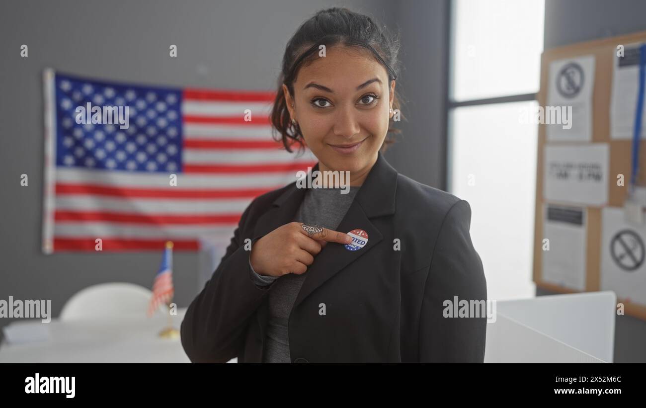 Young Hispanic Woman Pointing To I Voted Sticker Indoors With