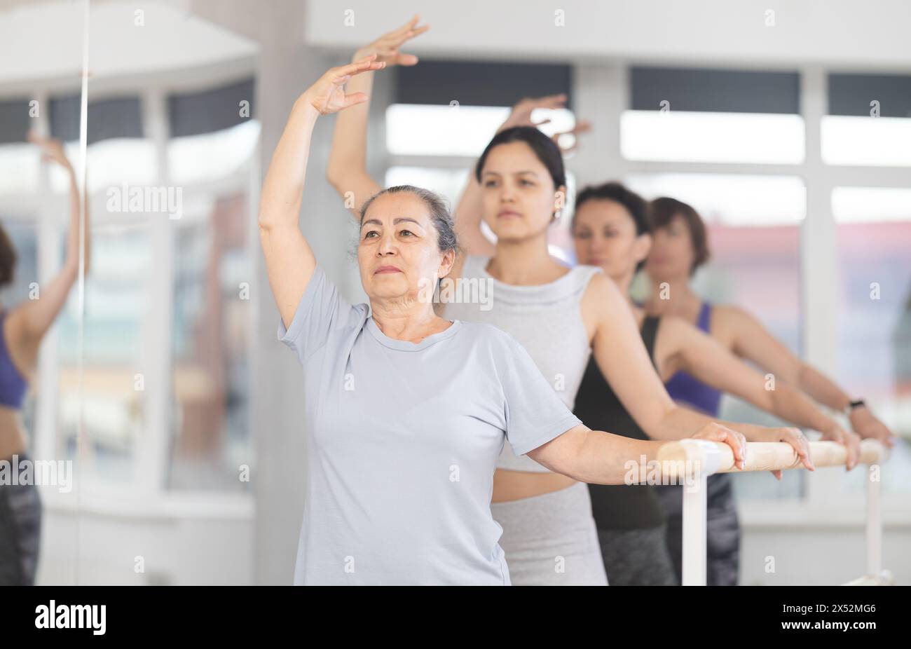 Group of women stand in fourth position at barre Stock Photo - Alamy