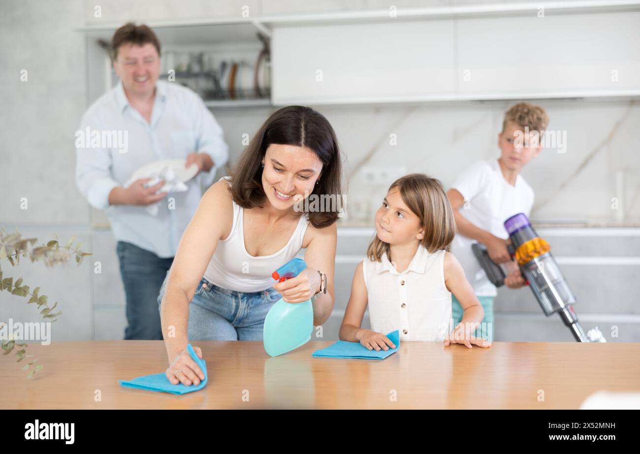 Happy family with two children doing cleaning in kitchen Stock Photo ...
