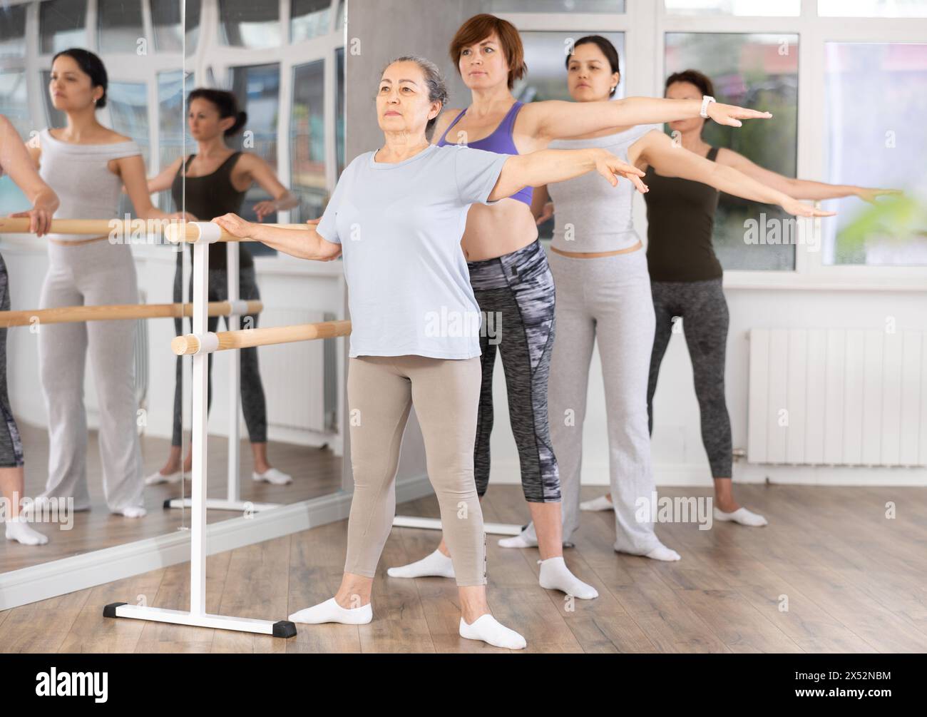 Group of women stand in second position at barre Stock Photo - Alamy
