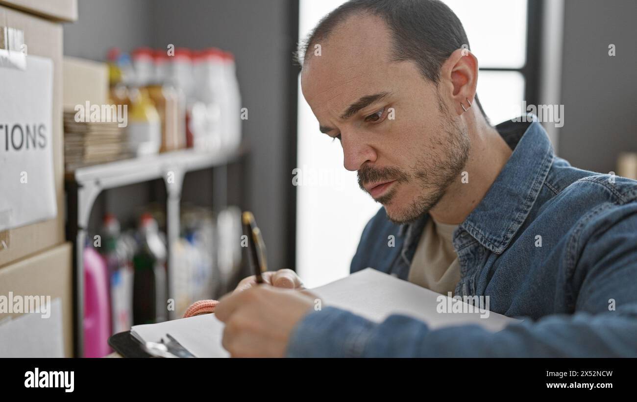 Hispanic bearded man writing in a notebook at a donation center ...