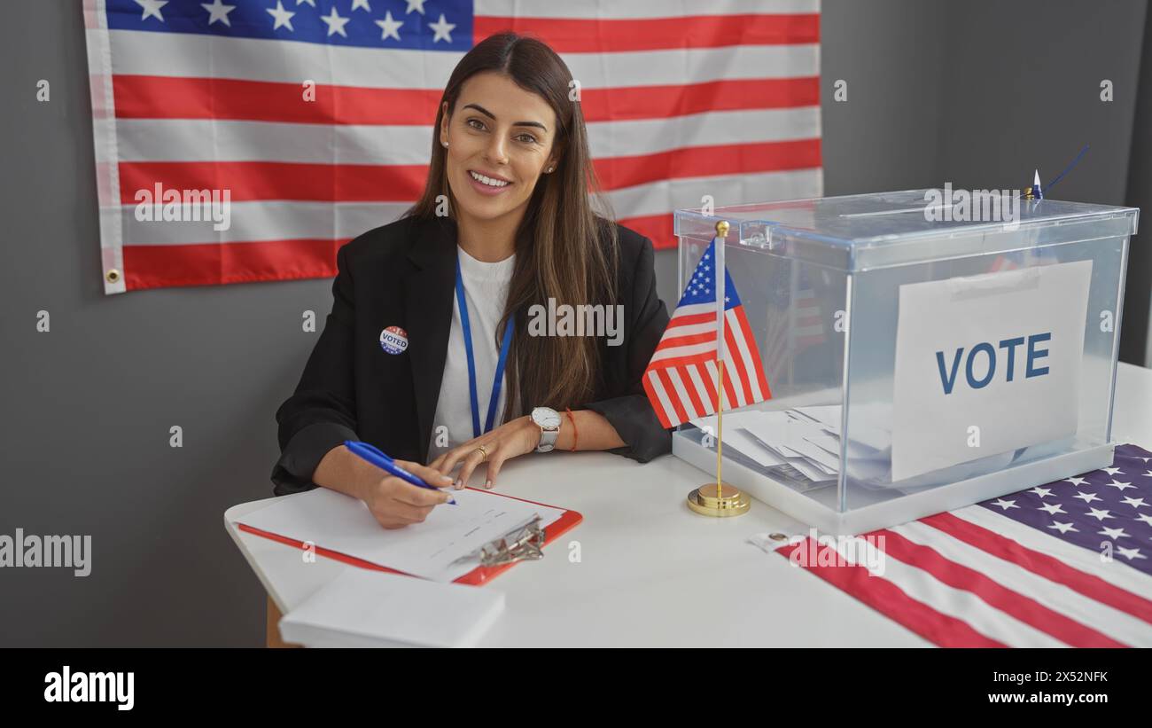 A smiling young hispanic woman sits indoors with an american flag ...