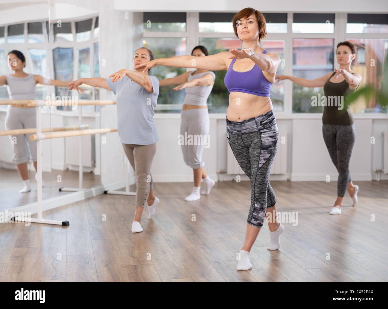 Graceful women of different ages practice various ballet movements in ...
