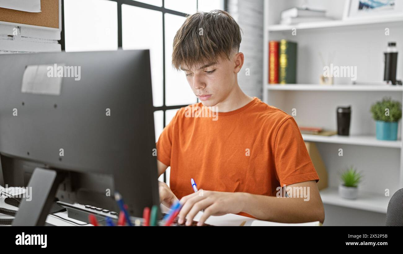 Focused teenage boy studying at a modern home desk setup, with a ...
