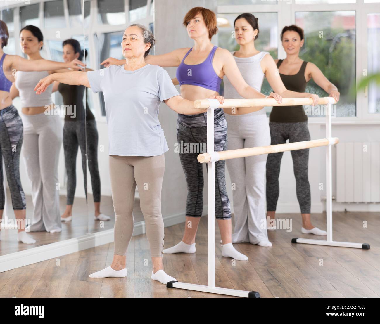 Group of women stand in second position at barre Stock Photo - Alamy