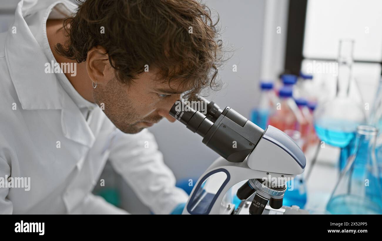 Hispanic researcher man examines samples using a microscope in a modern ...