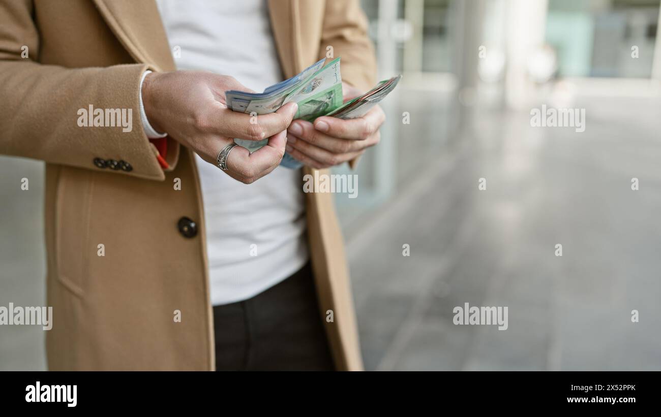Hispanic man counting malaysian ringgit in urban outdoor setting ...