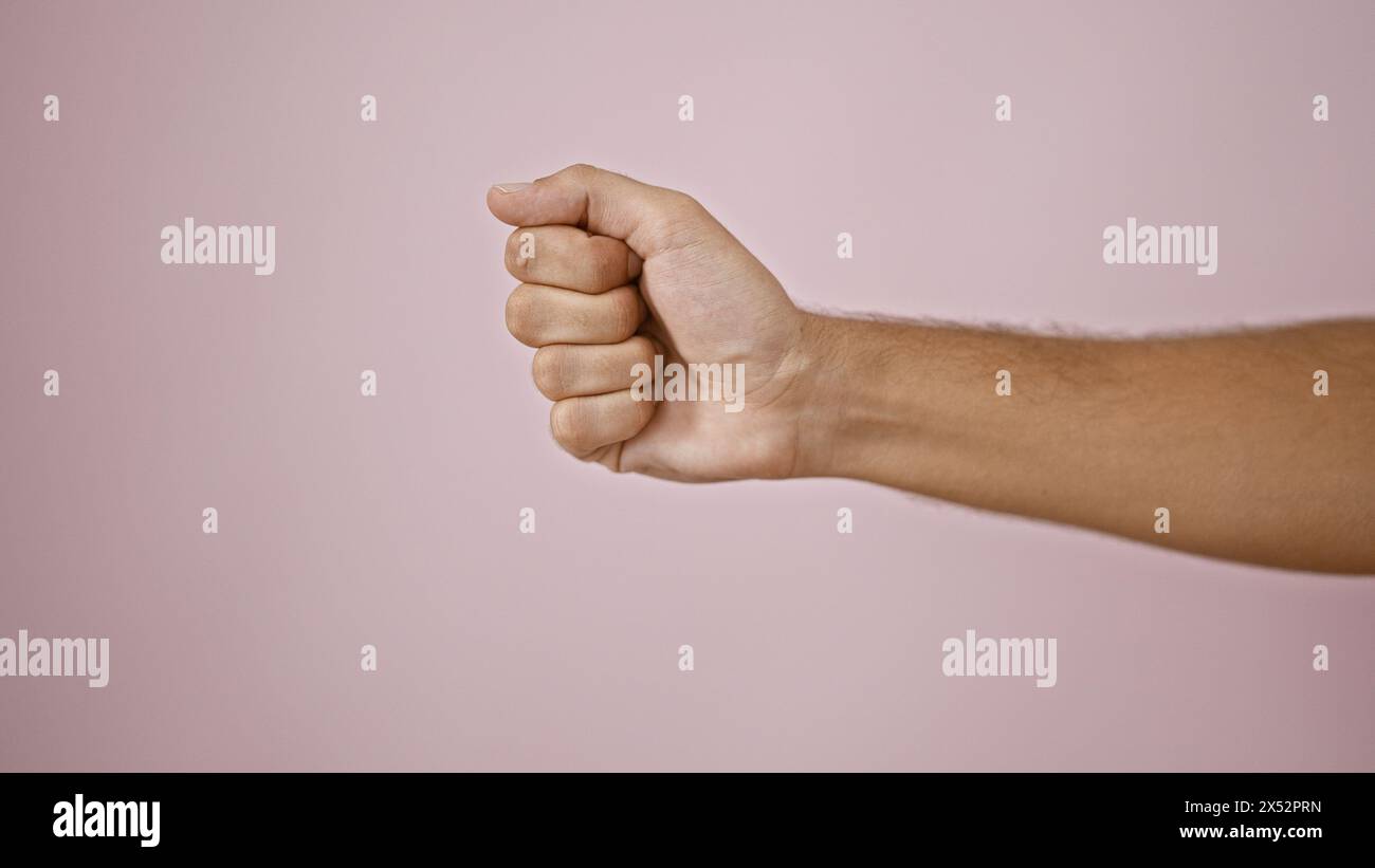 Close-up of a young man's clenched fist against an isolated pink ...