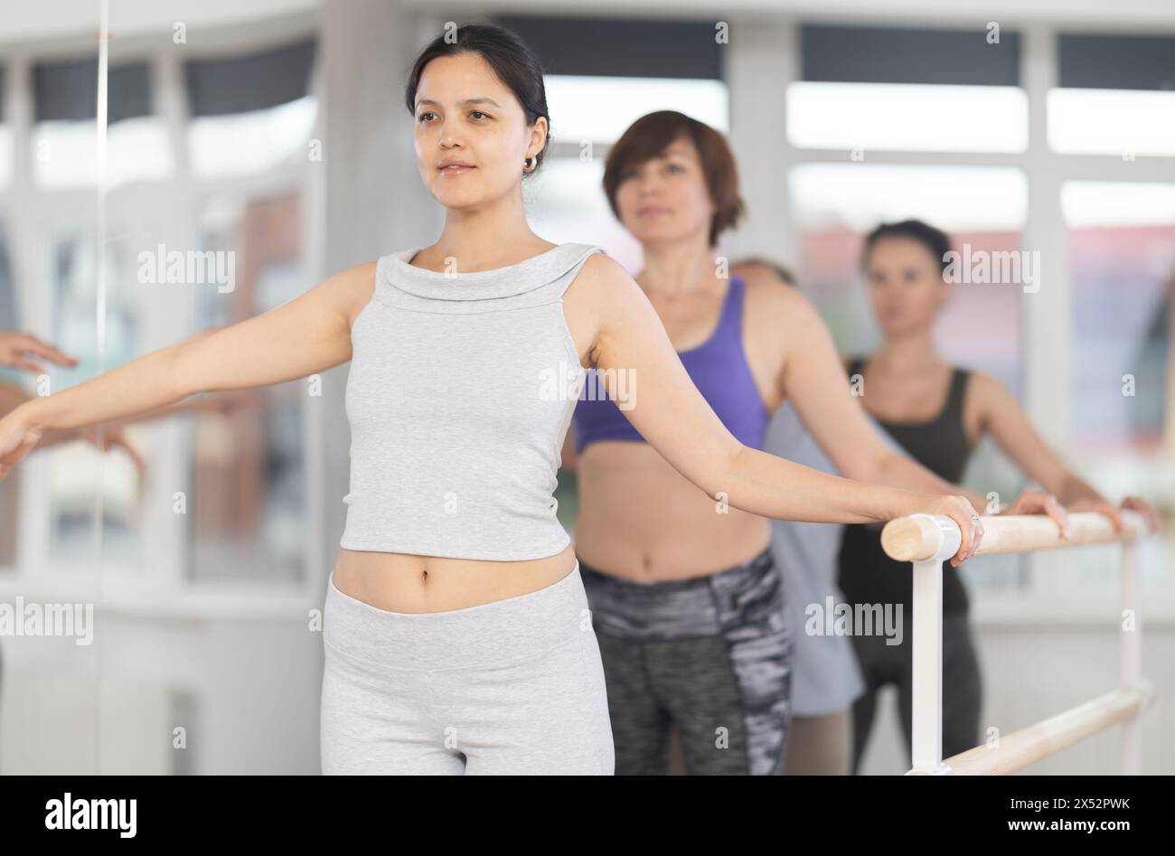Group of women stand in second position at barre Stock Photo - Alamy