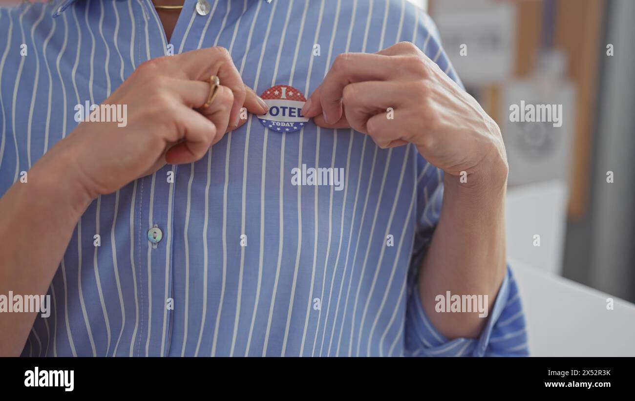 Caucasian woman in a striped shirt pins a 'voted today' button ...