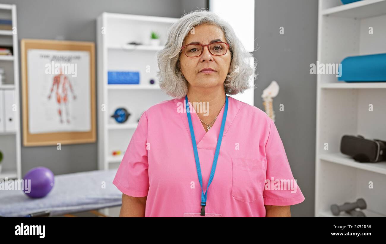 A middle-aged woman in medical scrubs stands confidently in a well ...