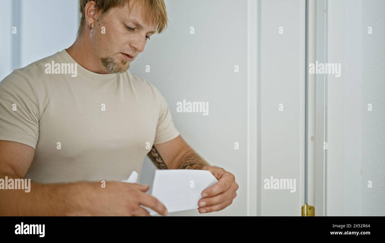 Handsome caucasian man with a beard reading a letter in a modern home ...