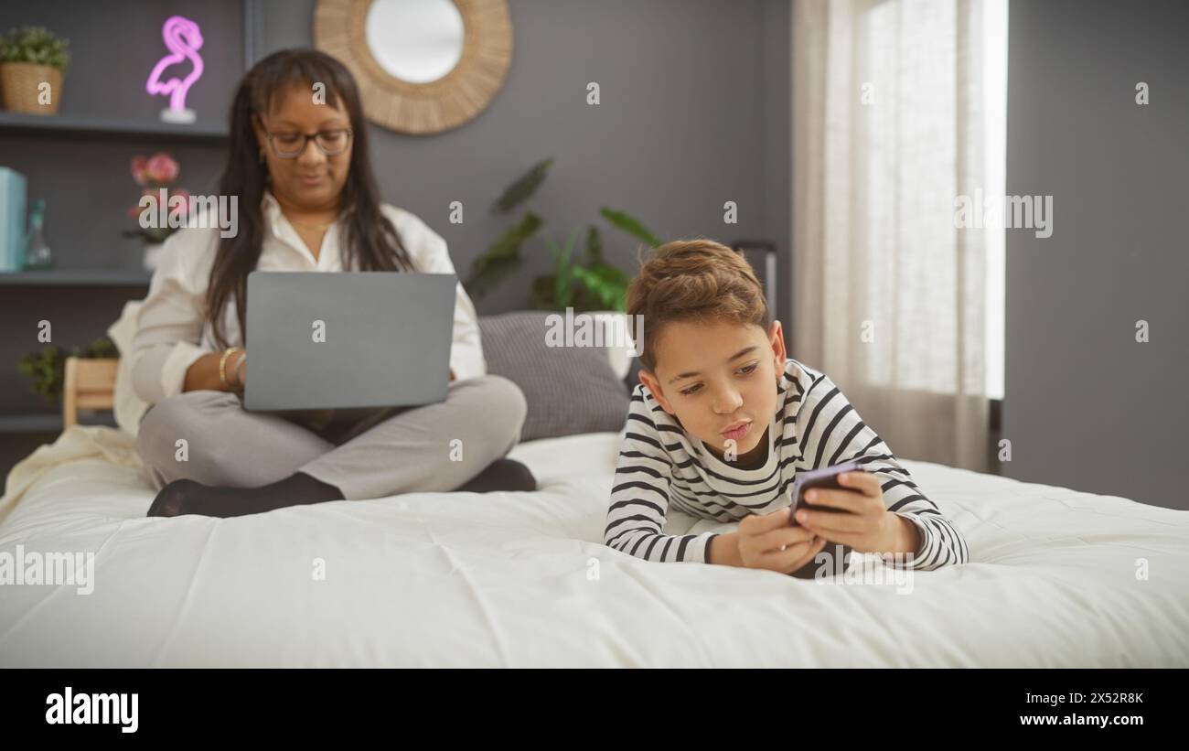 A woman and boy engage with technology in a cozy bedroom, depicting ...