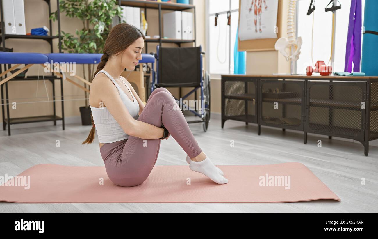 Woman exercising in a therapy room with equipment and anatomical charts ...