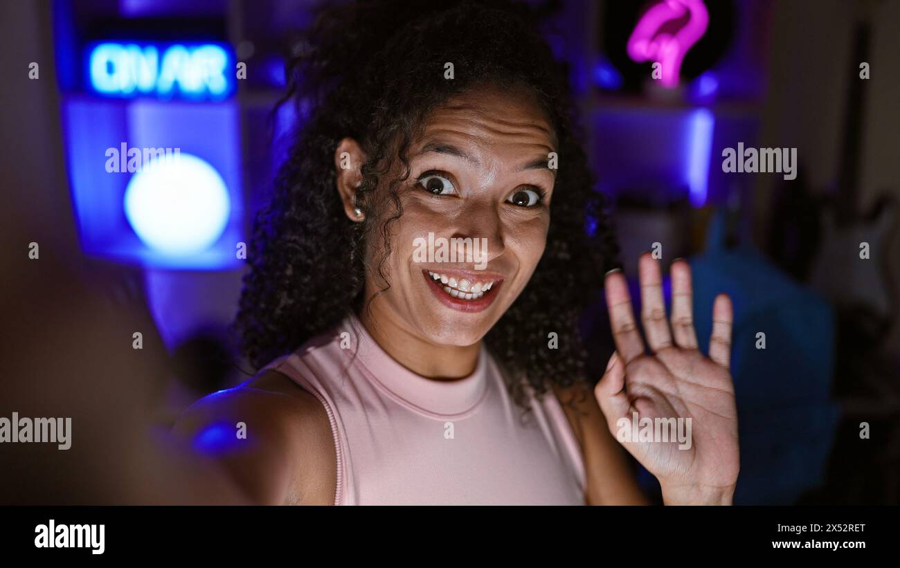 Confident curly-haired young hispanic woman streamer rocks her gaming ...