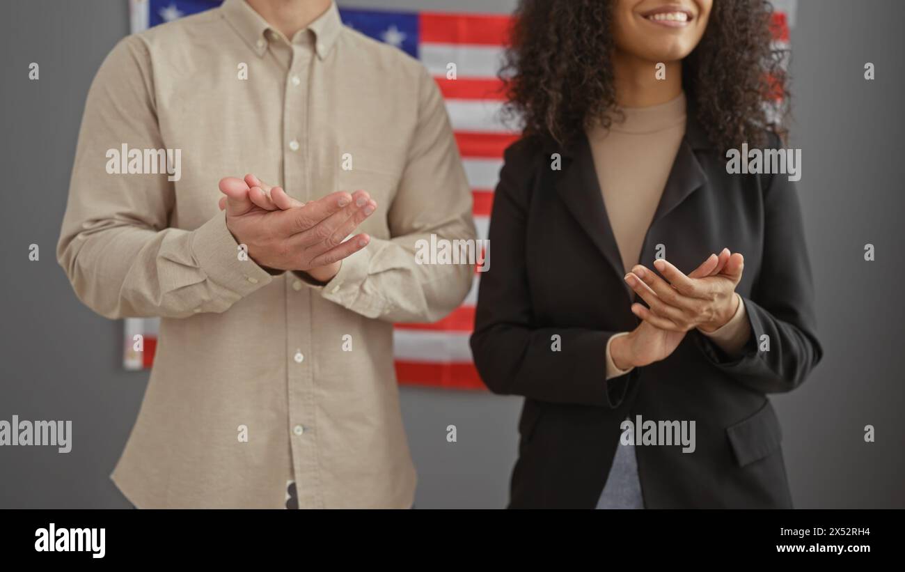 Man and woman in professional attire clapping hands in an office with ...