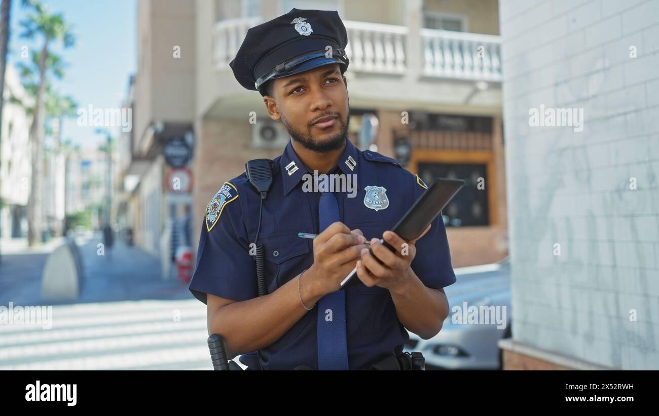 African american policeman taking notes on a tablet in a sunny urban ...