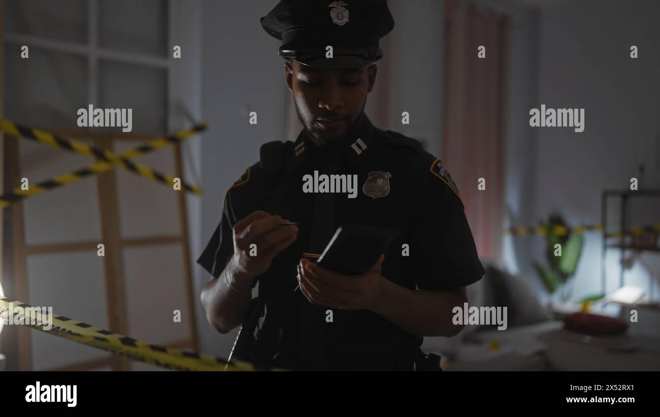 African american policeman taking notes at a dimly lit indoor crime ...