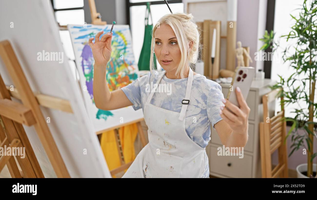 Spunky young blonde artist draws during vibrant video call at snug art ...