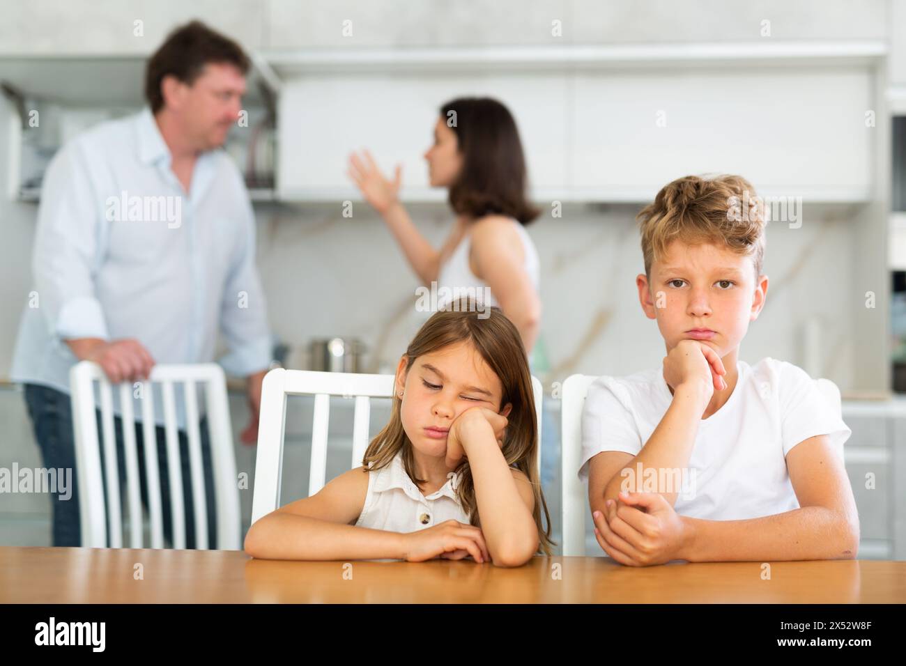 Brother and sister sit at table during quarrel between parents Stock ...