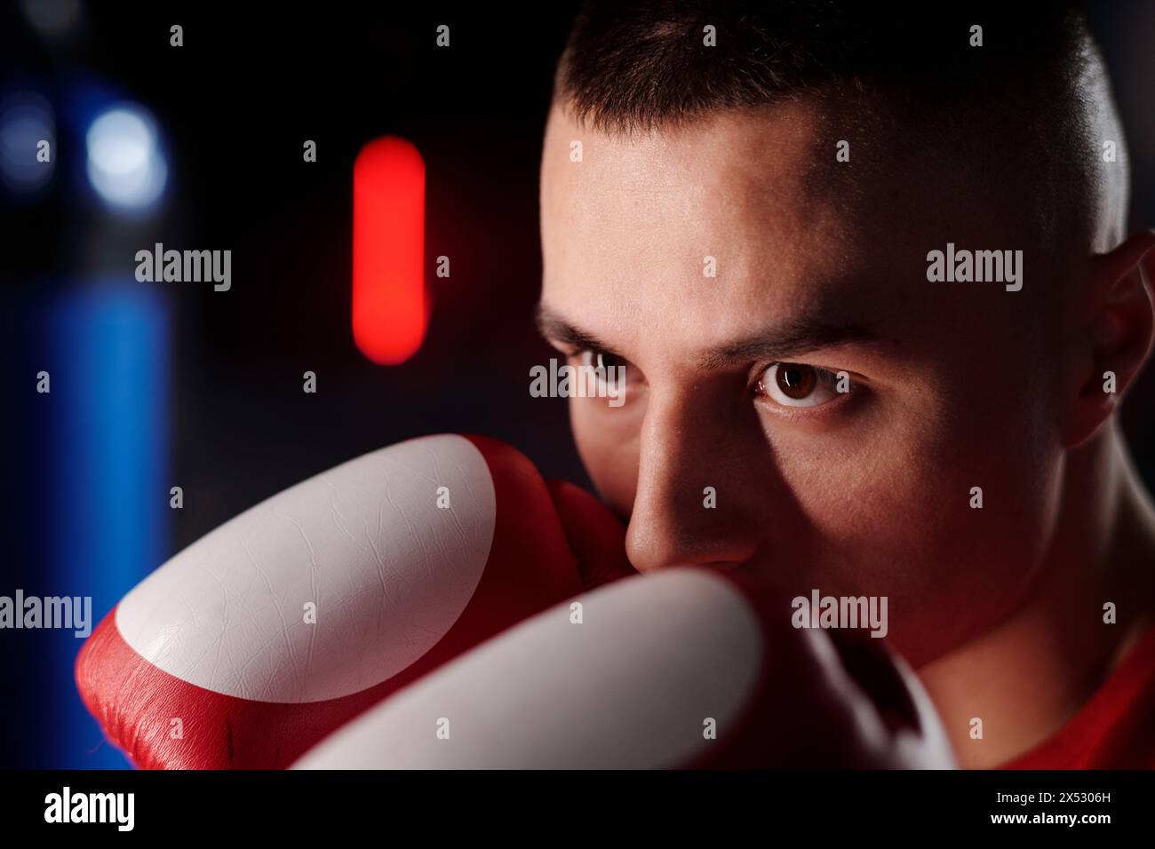 Face of young male boxer looking forwards and keeping hands in boxing ...