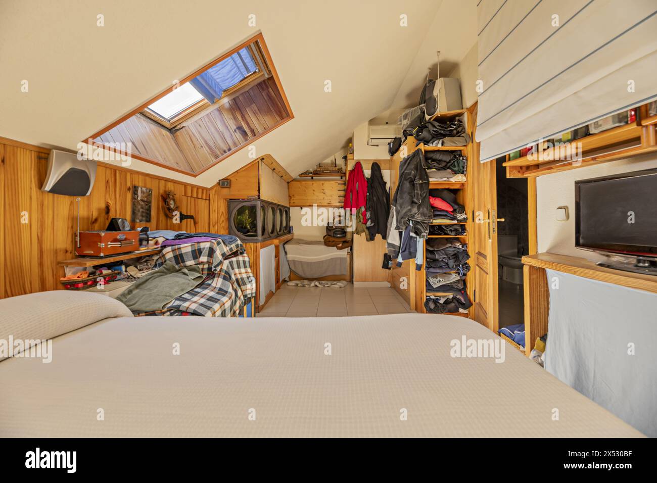 attic bedroom with skylight in the ceiling and wooden tongue-and-groove ...