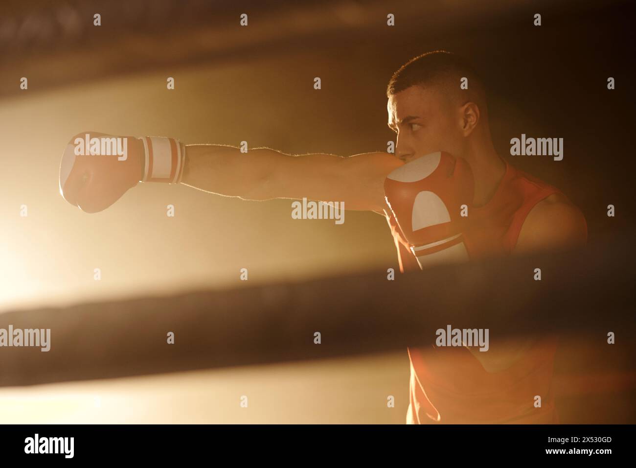 Young boxer holding left arm bent in elbow by his face while kicking ...