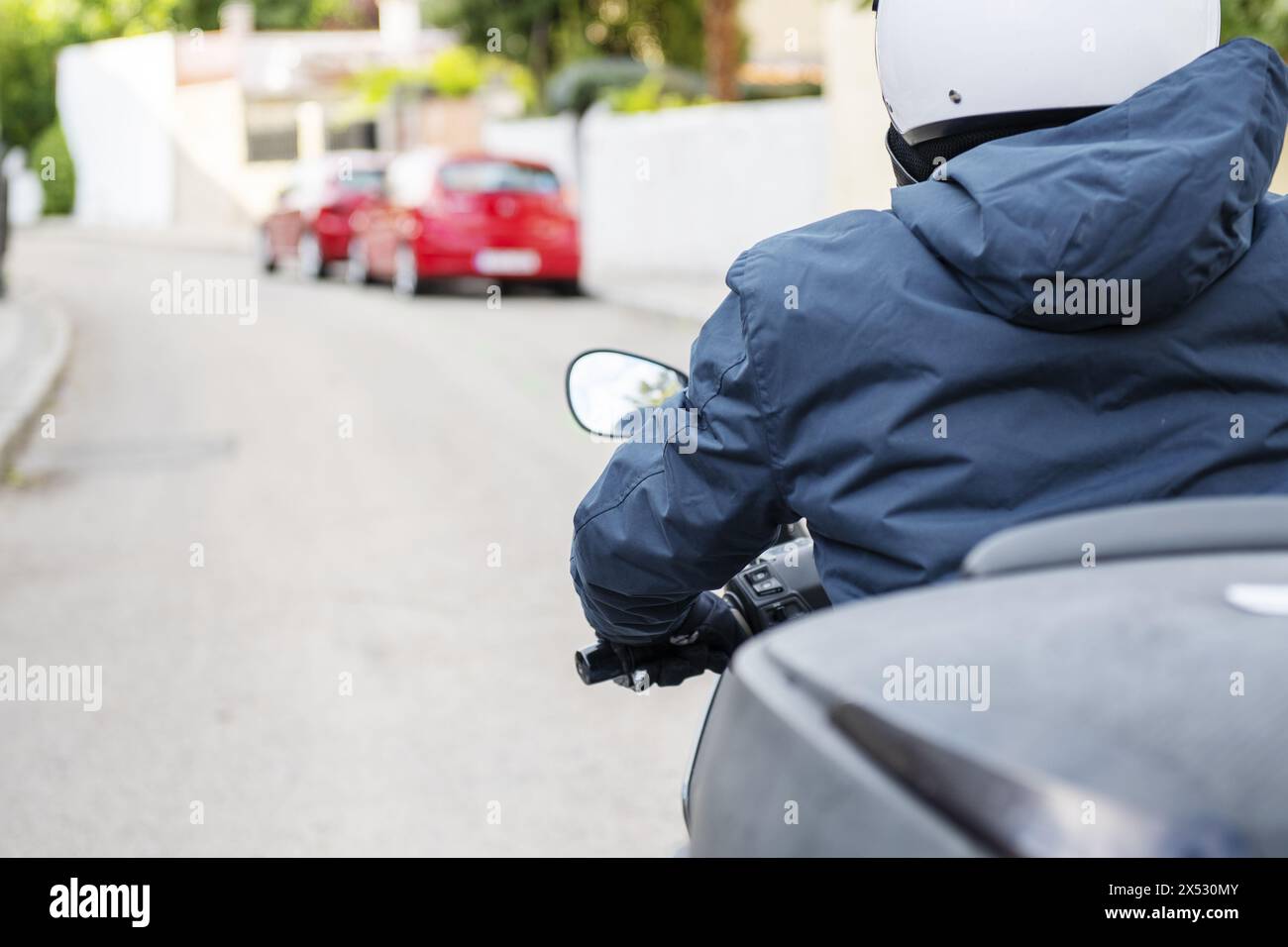 A delivery man on a motorcycle with a gray box driving through the city ...