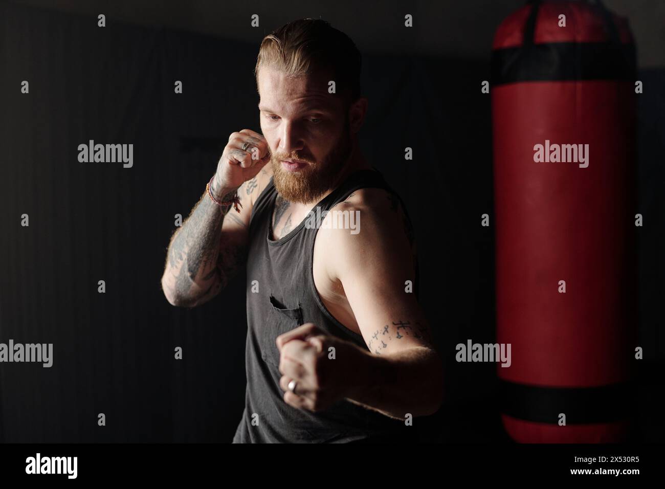 Light falling on front part of young muscular man with tattoos on arms ...