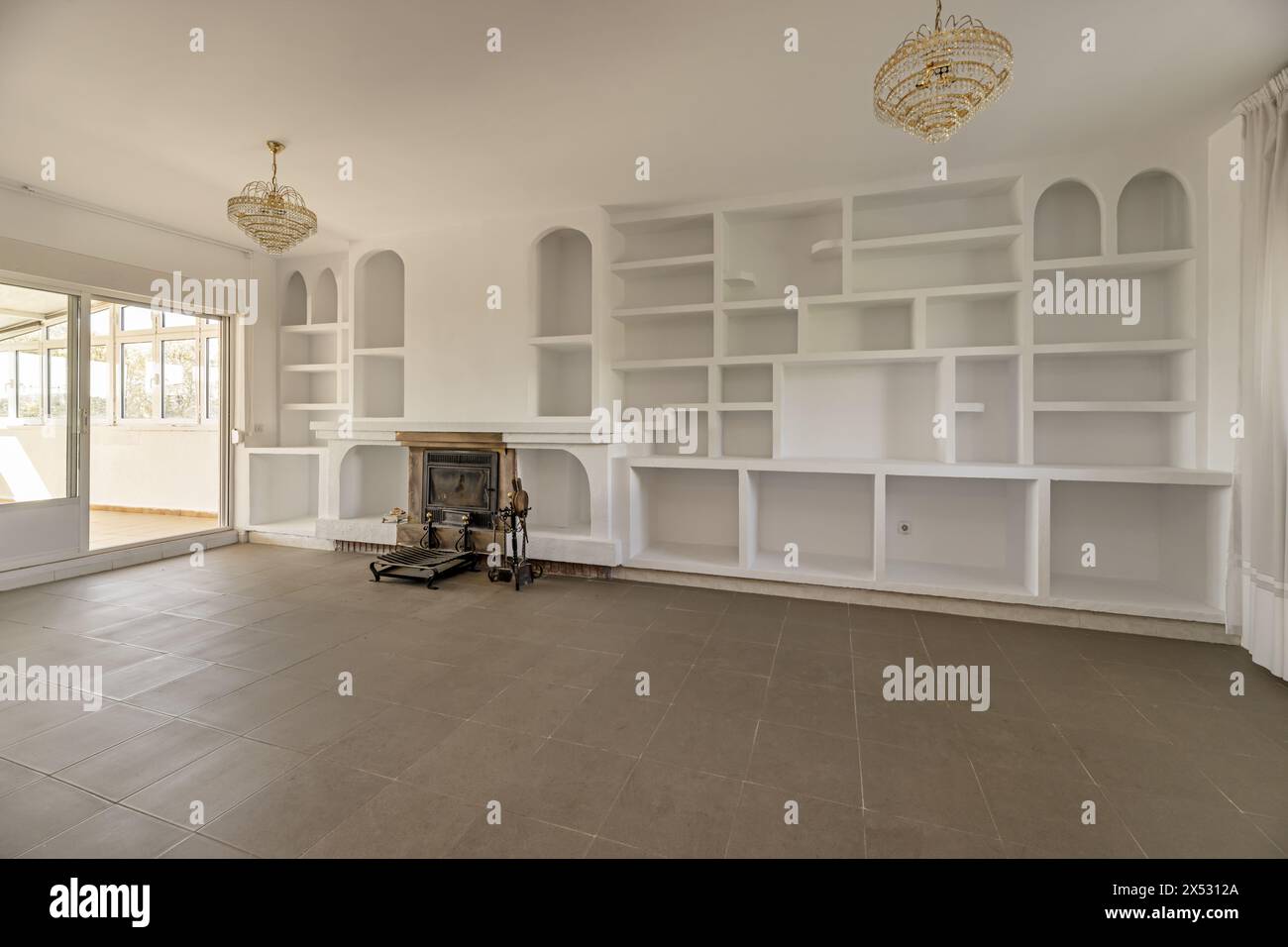 A large empty living room with built-in shelves and a fireplace with ...