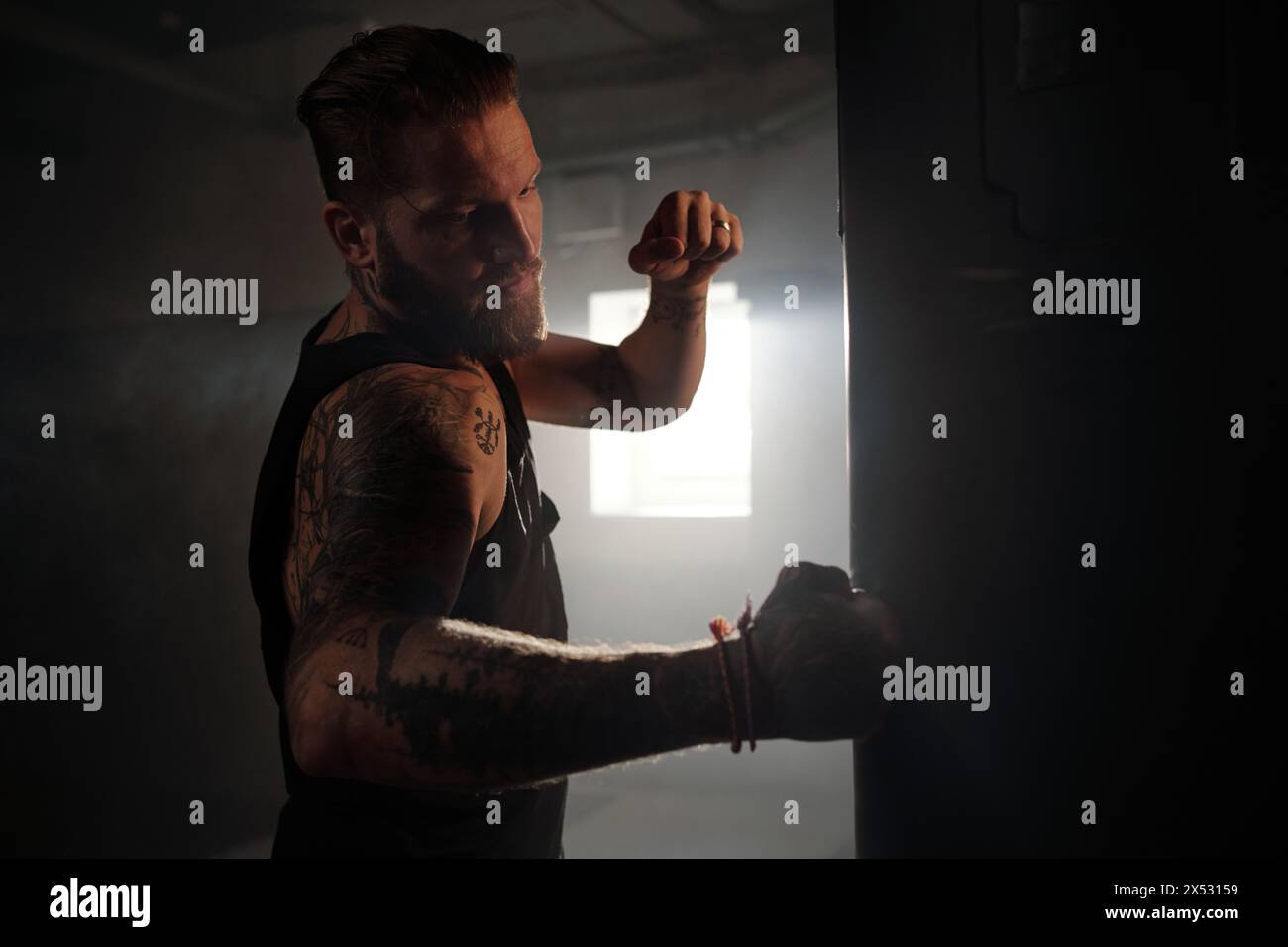 Young muscular man with tattoos on arms, shoulders and chest hitting ...