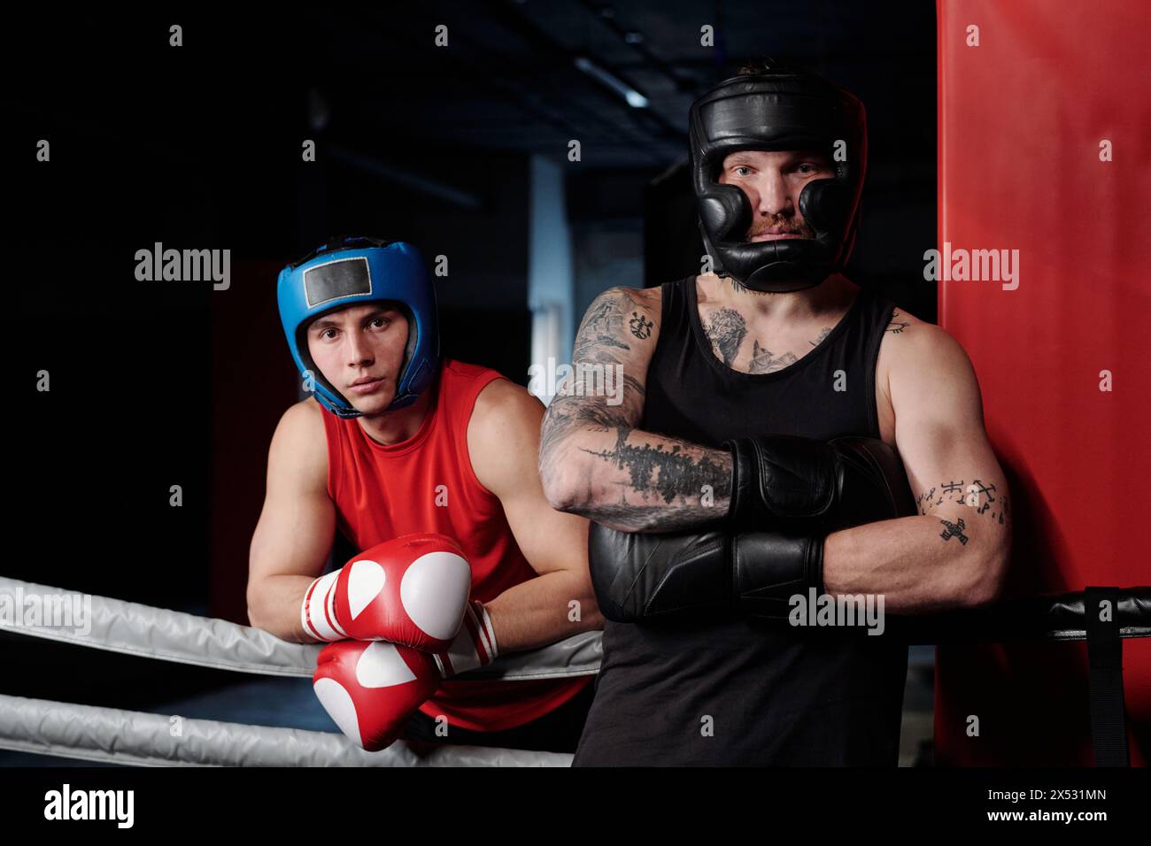 Two young boxers in black and red sportswear and protective sports ...