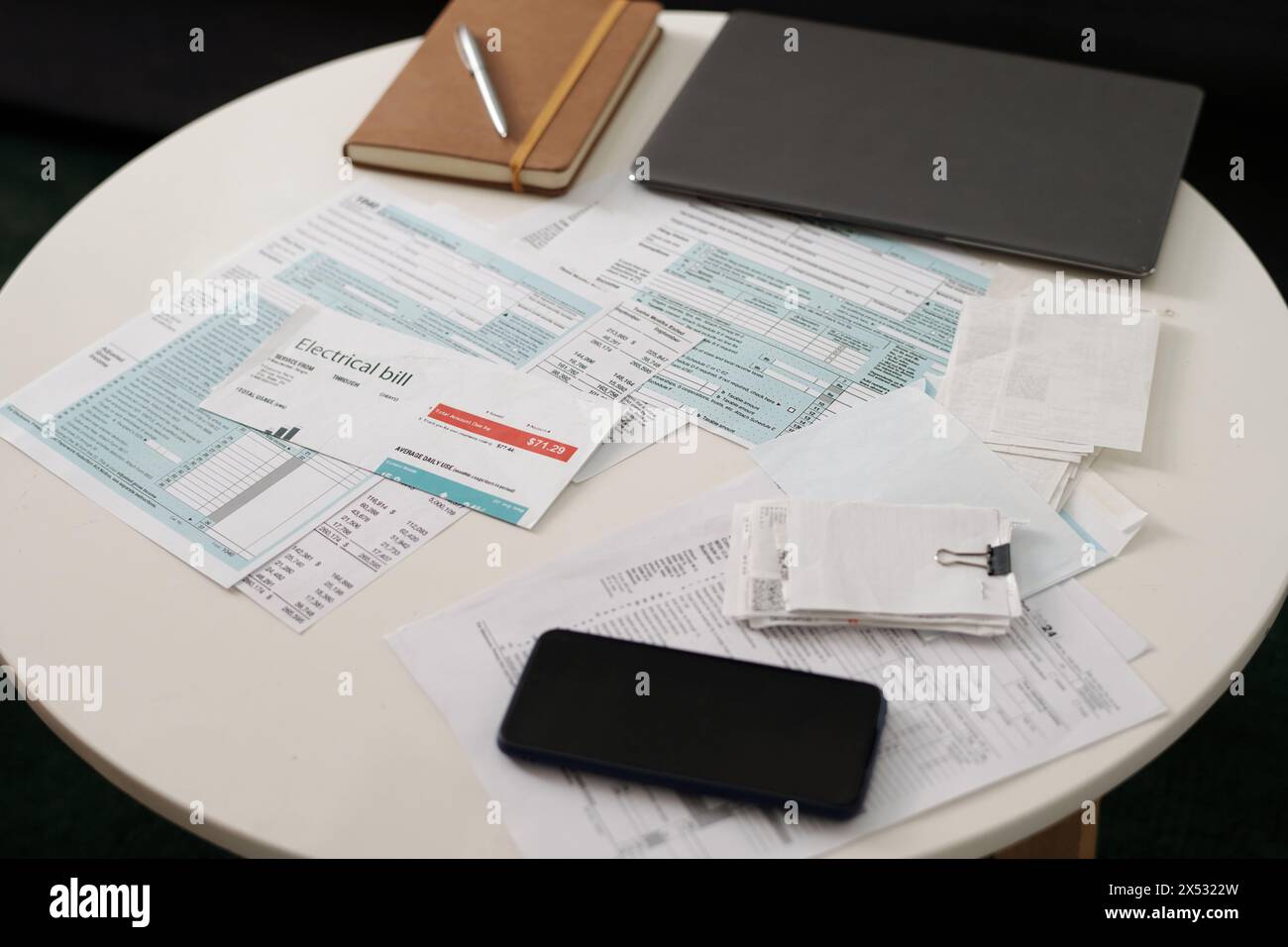 Folded unpaid electrical bill lying on round table over other papers ...