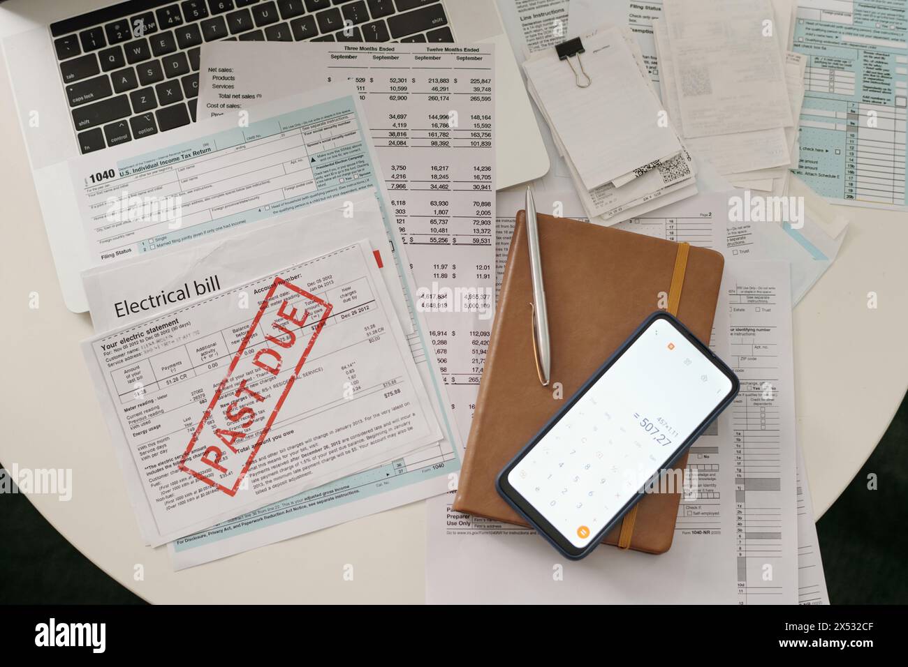 Overview of laptop keyboard, electrical bill with past due stamp ...