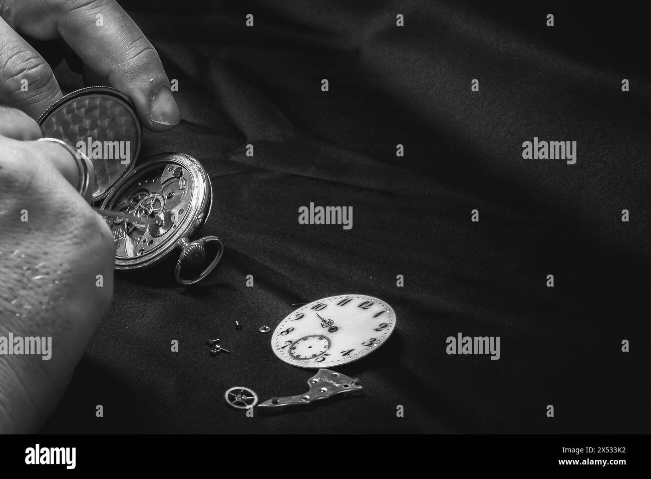 Opened pocket watch is repaired, dial and inner parts visible, on black ...