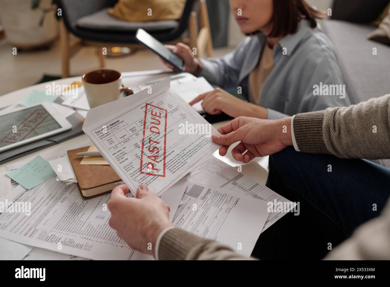 Unpaid financial bill with past due stamp in hands of young man sitting ...