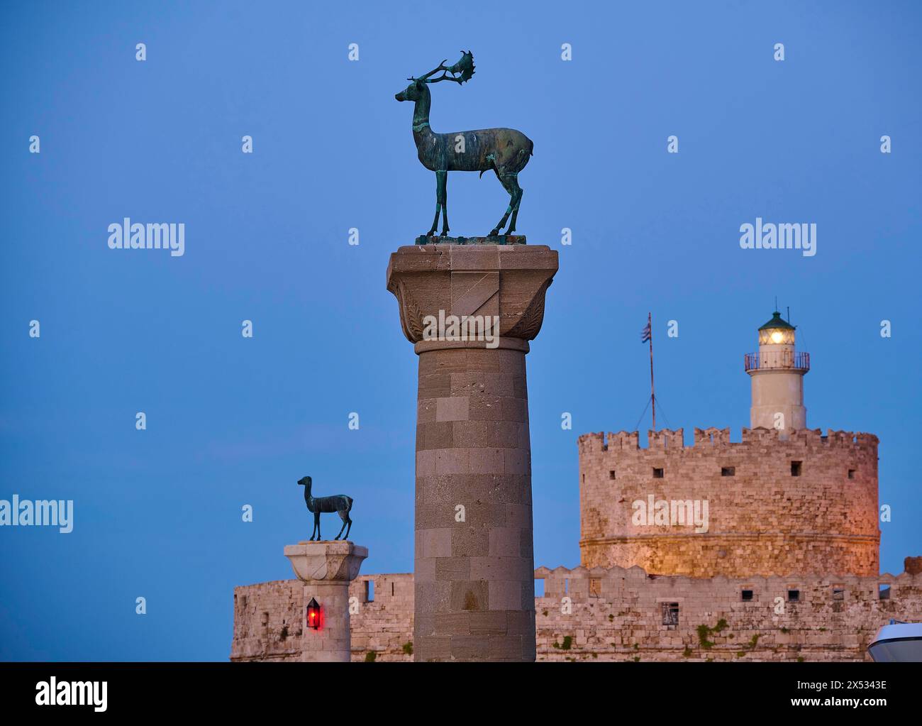 Deer statue on a pillar in front of a fortress wall and a lighthouse at ...