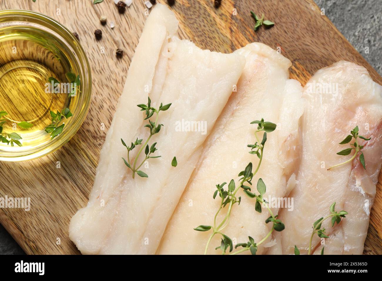 Raw cod fish, microgreens, oil and spices on grey textured table, top ...