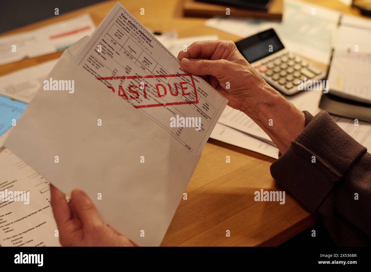 Hands of senior woman taking housing payment bill with past due stamp ...