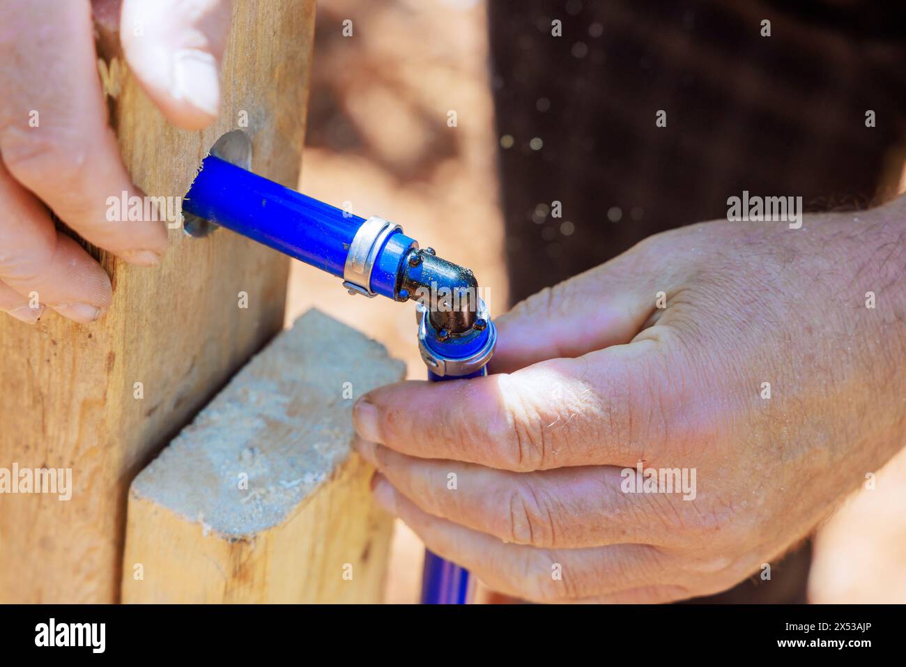 An experienced plumber connects blue PVC pipe to water piping system ...