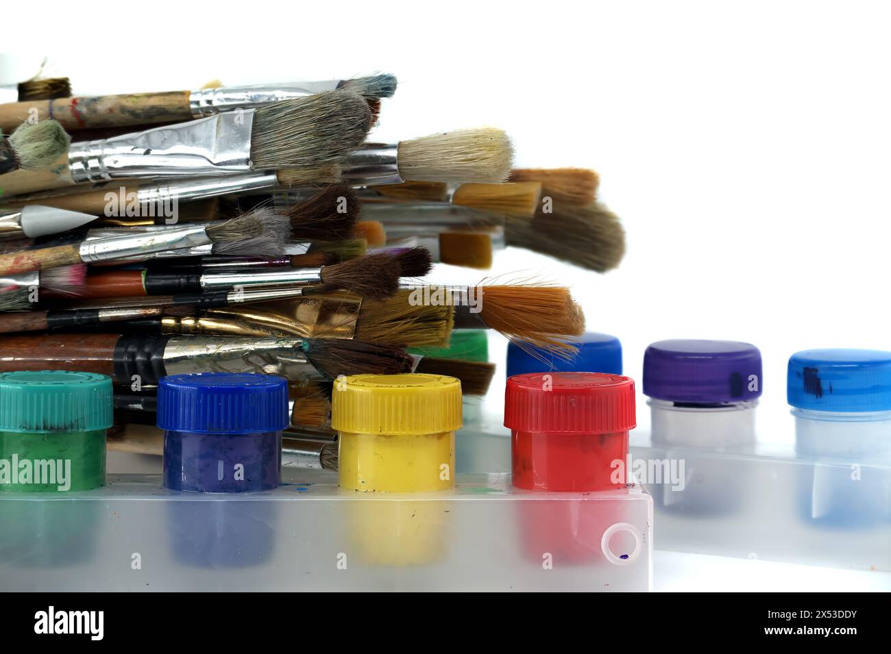 Array of paintbrushes of different sizes and colors alongside cans of ...