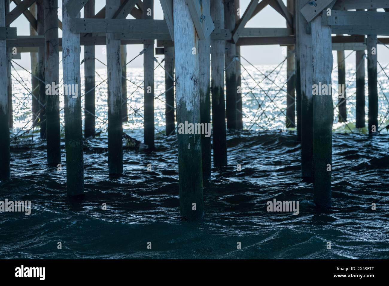 This image offers a serene yet powerful view beneath a pier, where ...